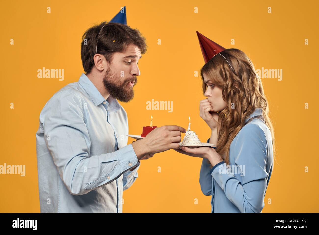 Birthday party man and woman on a yellow background in hats with a cake ...