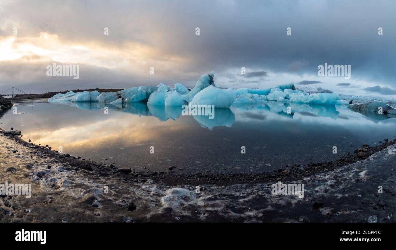 Iceberg Reflection on water at sunset, golden colors and blue ice Stock ...