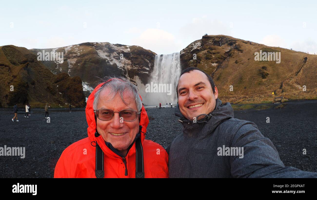 Father and son laughing with Skogafoss waterfall behind Stock Photo - Alamy