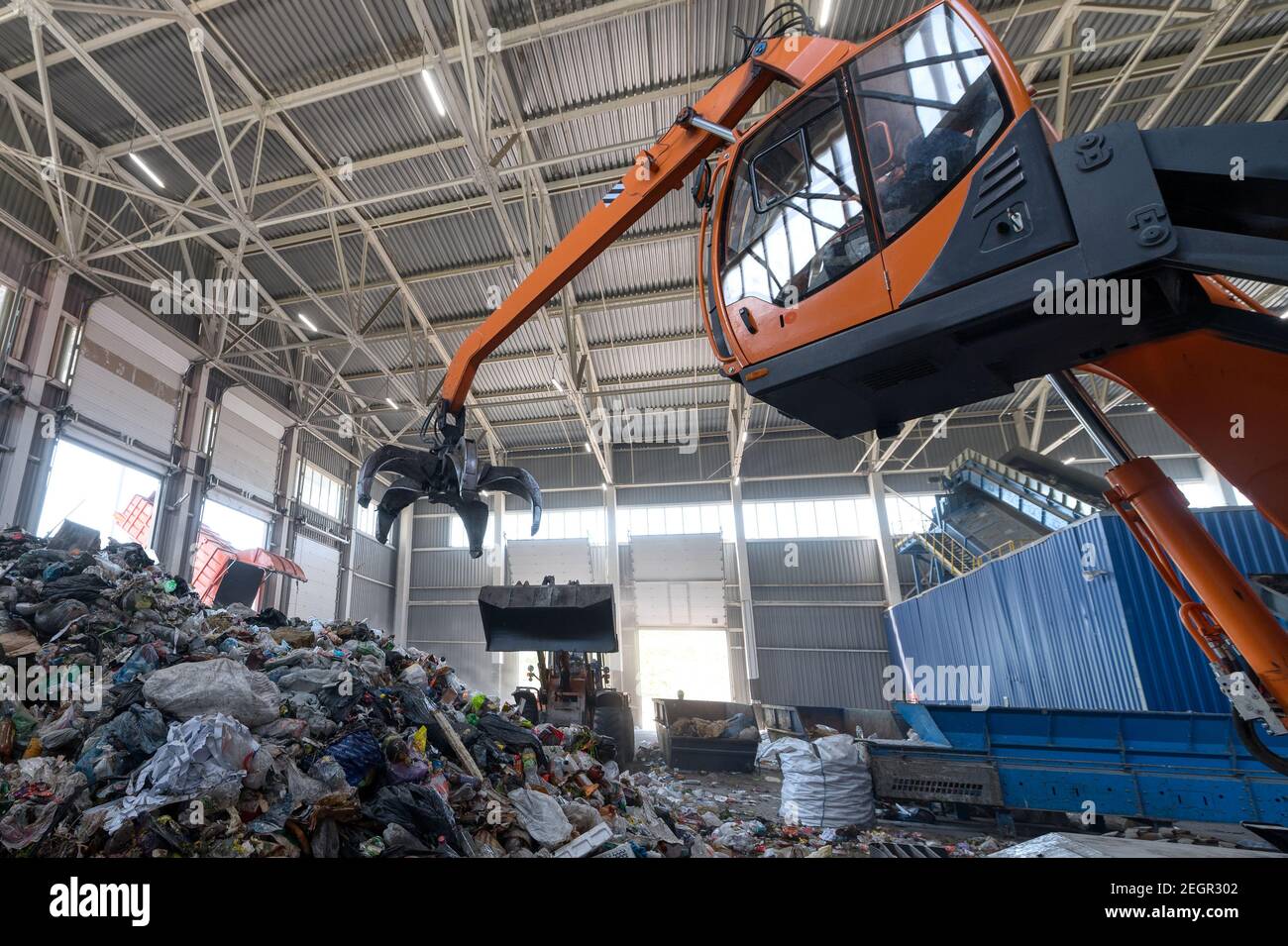 Waste sorting and recycling plant. Loader and grab crane are handling ...
