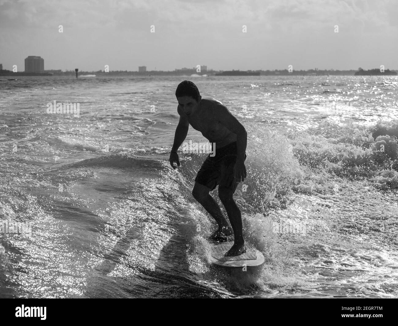 Black and white of male wake surfing at sea, shadow cast over water ...