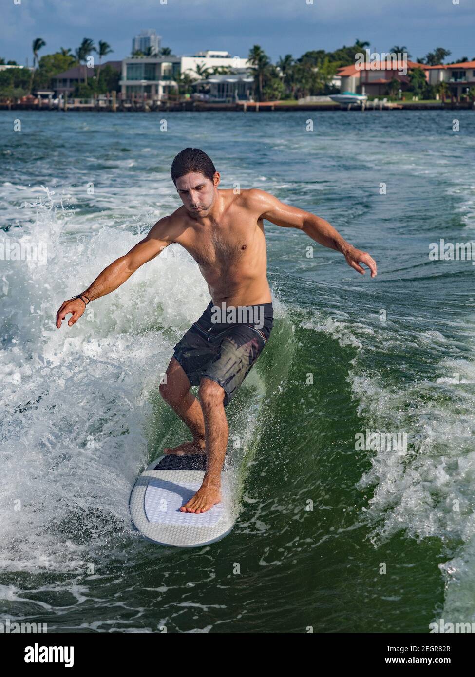 Athletic man rides a wave while wakesurfing in Miami, wearing sun ...