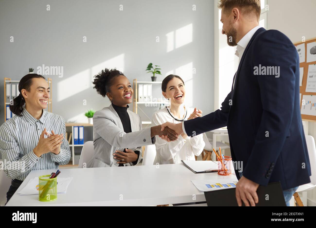 Young multiracial business team shakes hands with a man welcoming him ...