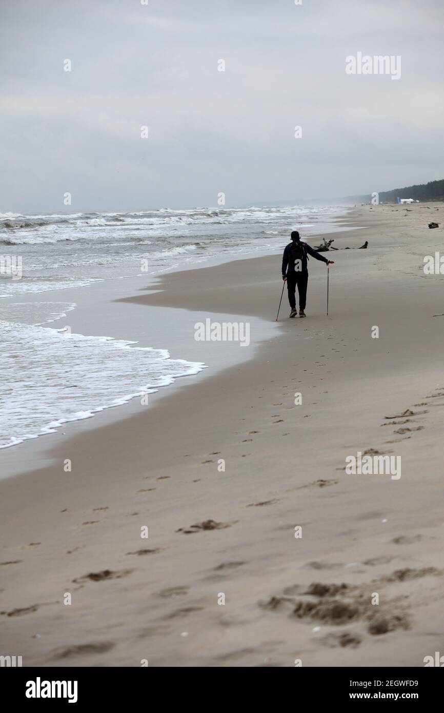 Active and healthy lifestyle. Nordic walking on a sandy beach sea shore ...