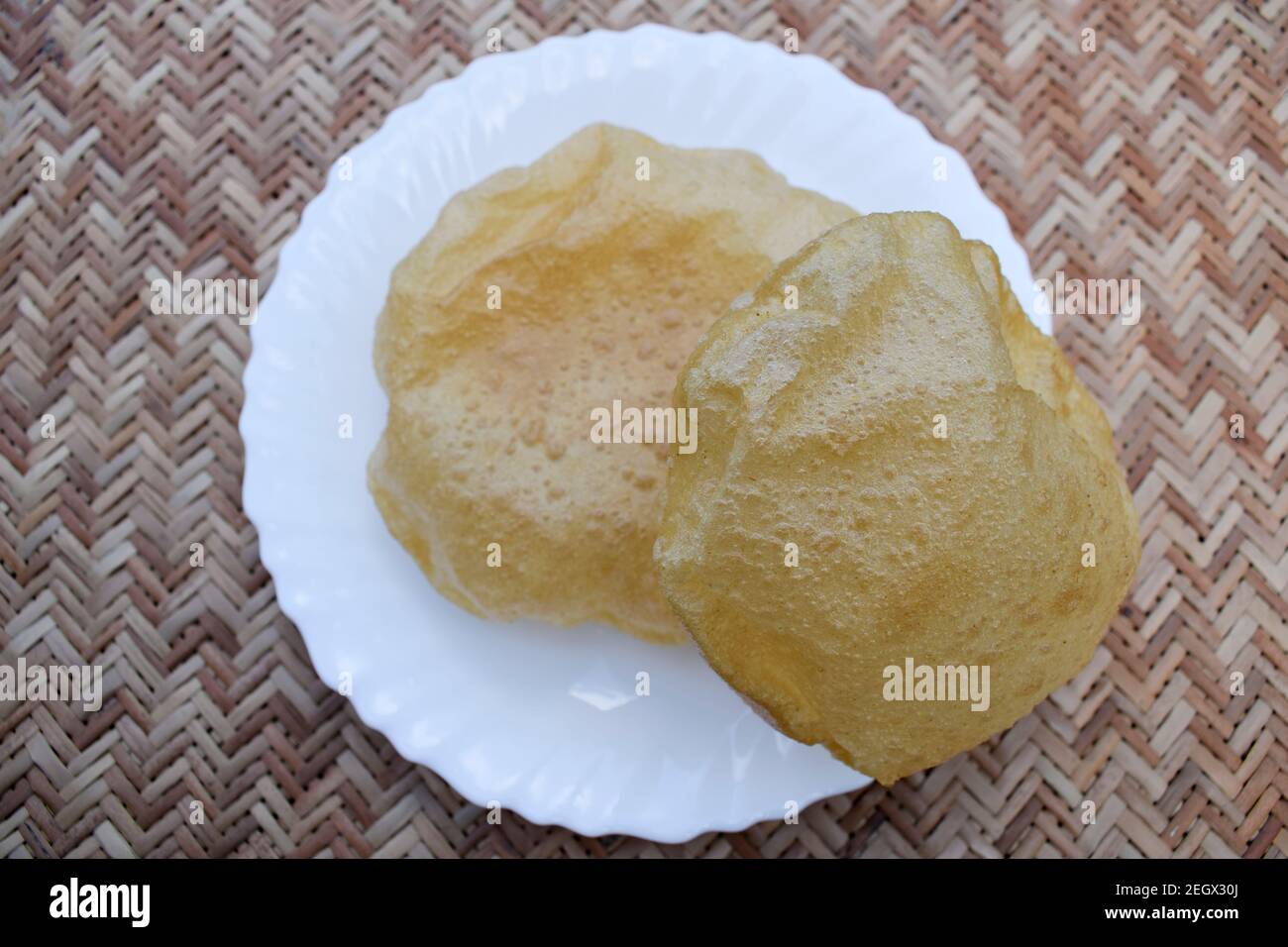 Plain puri or Indian deepfried bread served on white plate. Full blown ...