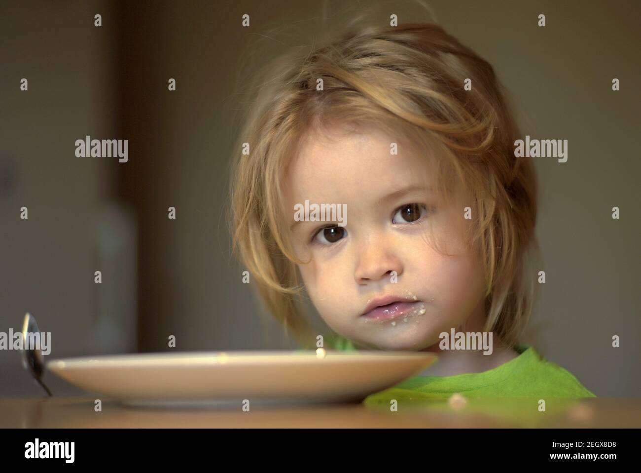 Child with empty plate, spoon after eating. Little boy with dirty mouth ...