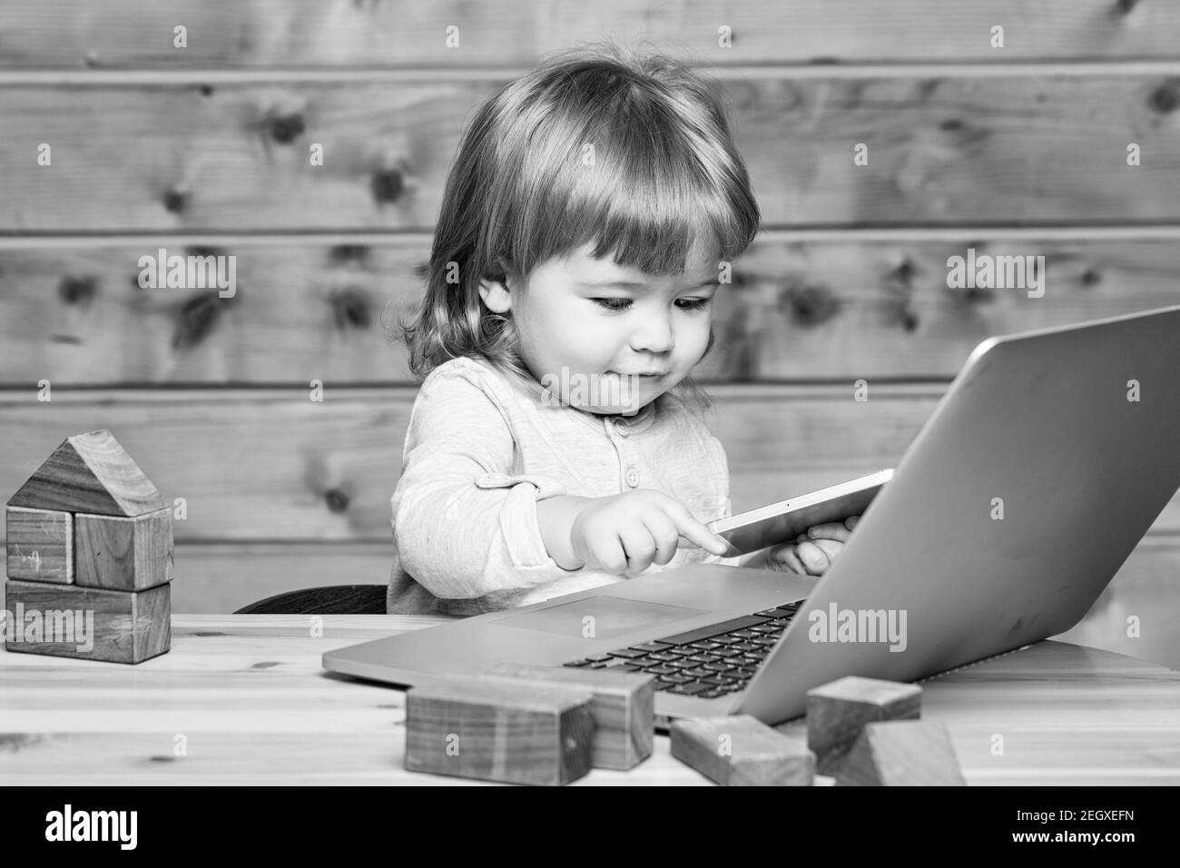 Cute funny little baby playing on computer and mobile phone near toy ...