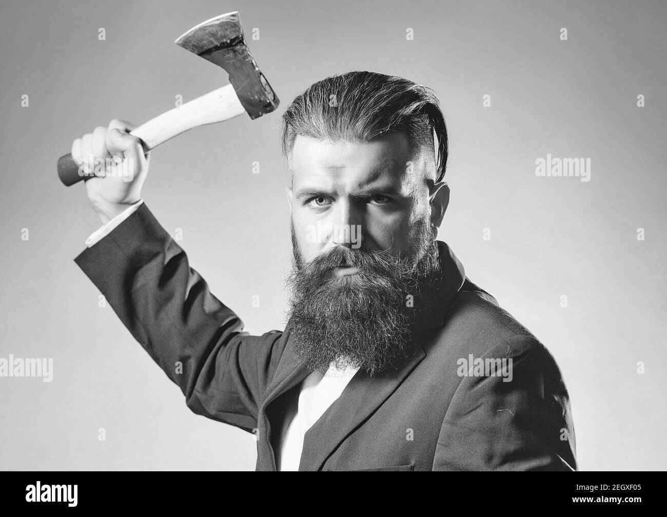 Bearded man with long beard and moustache holding sharp axe in studio ...