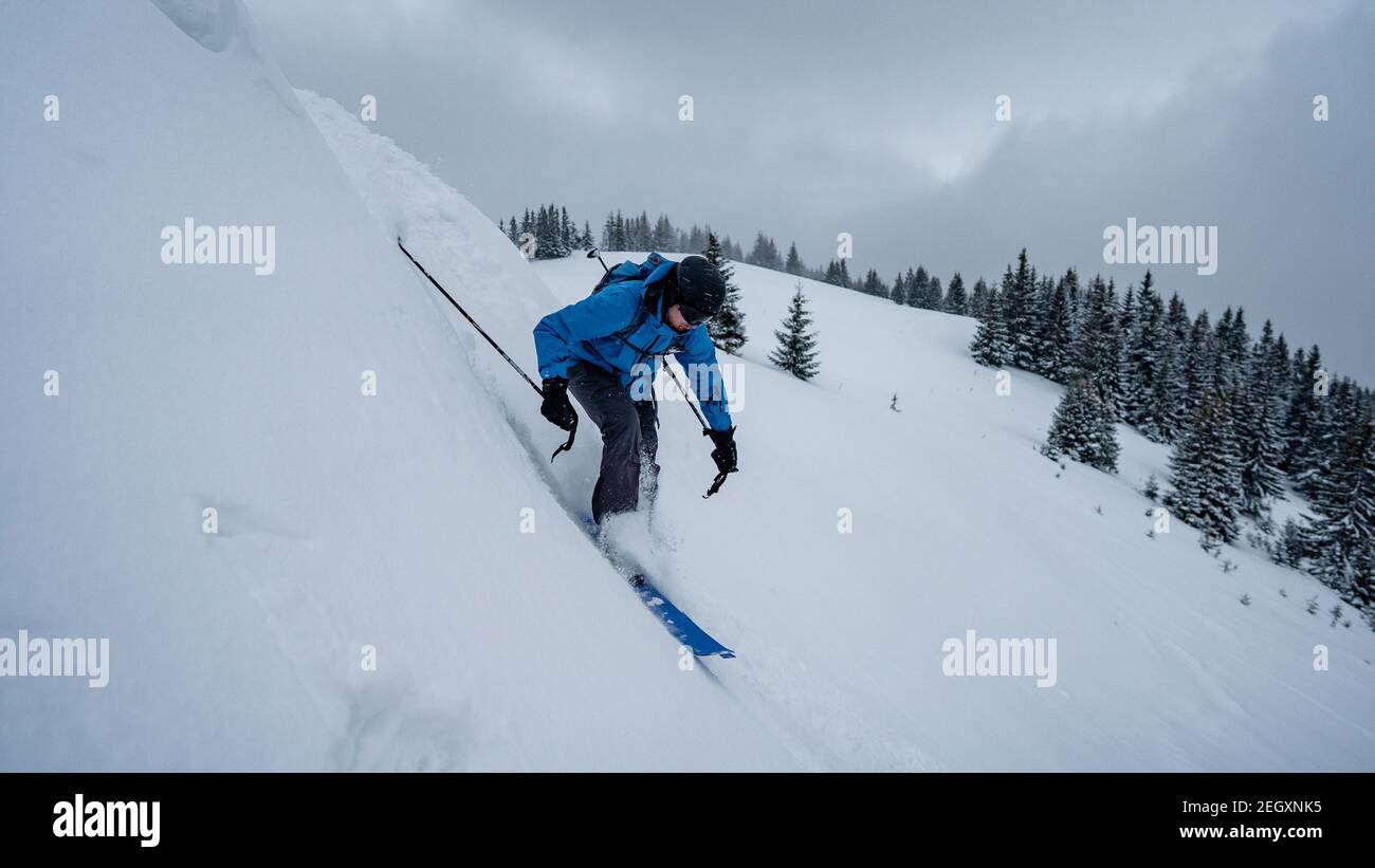 Skier skiing downhill in high mountains during windy cold weather. Snow ...