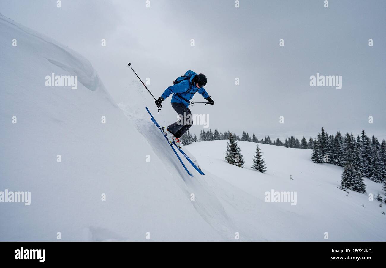Skier skiing downhill in high mountains during windy cold weather. Snow ...