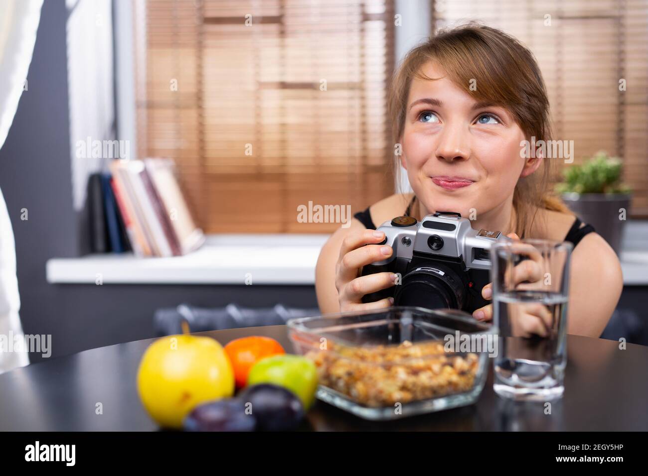 A young blogger takes a photo of her cooked food with a camera. He ...