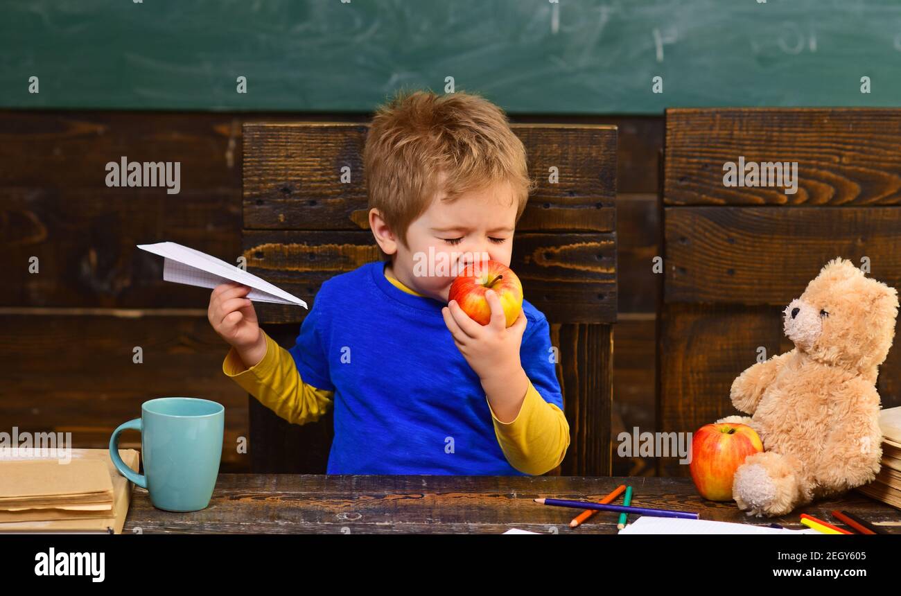 Kid eating apple with pleasure in class. Cute boy biting fruit with his ...