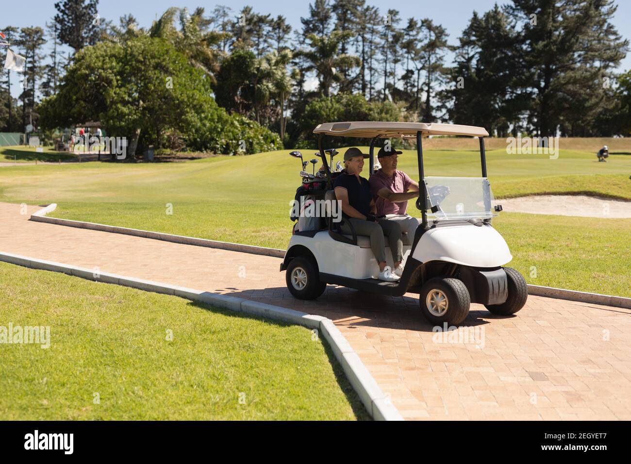 Caucasian senior man and woman driving golf buggy on golf course ...