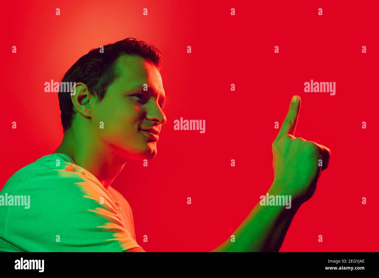 Pointing. Caucasian man's portrait isolated on red studio background in ...