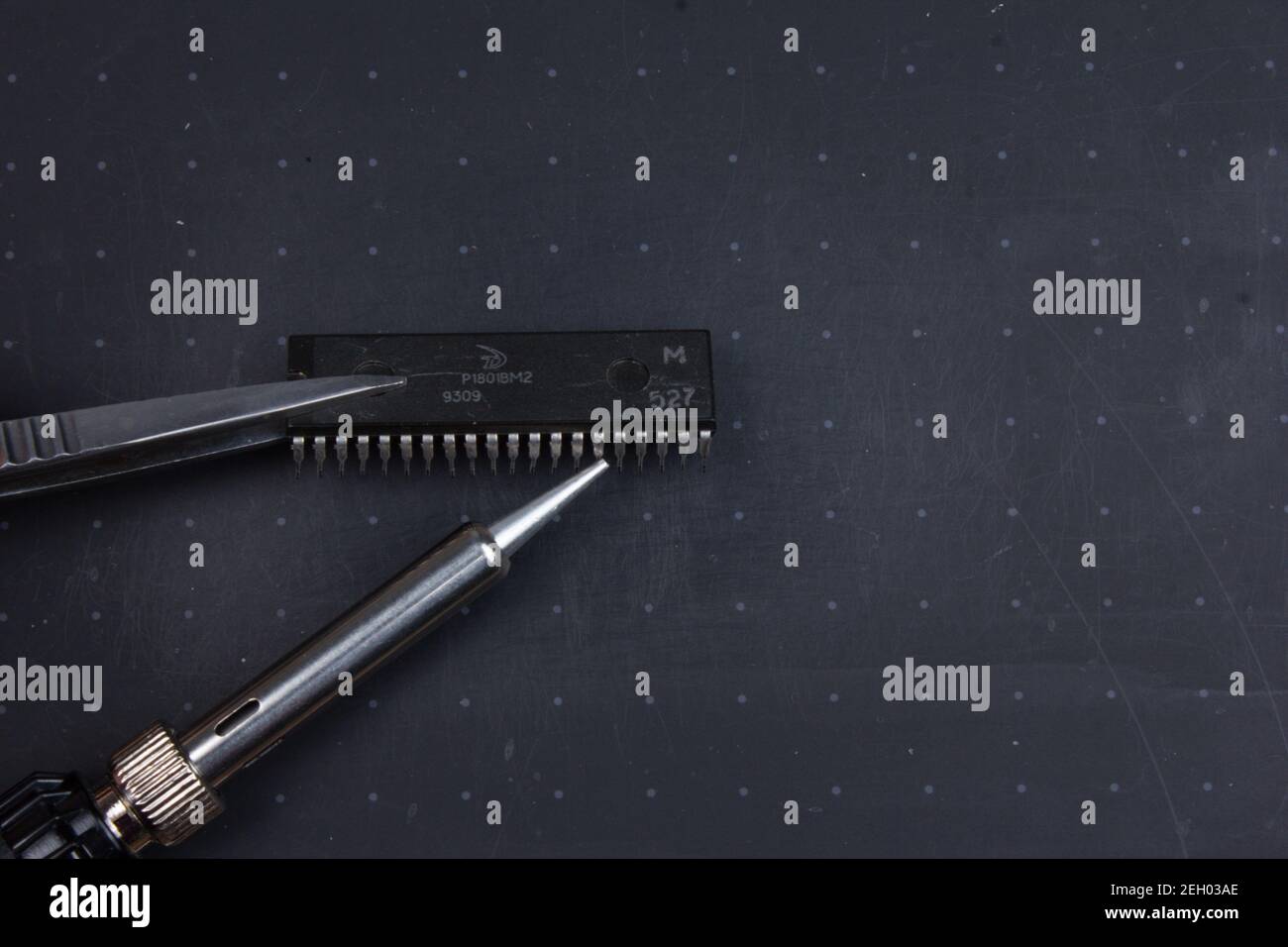 Soldering tools. Soldering iron, tweezers and microchip, on a black ...