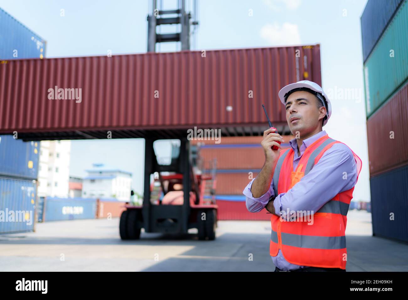 Caucasian foreman man is using walkie talkie to command his workers ...
