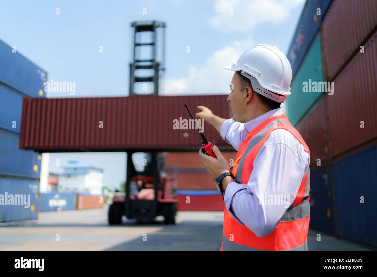 Caucasian foreman man is using walkie talkie to command his workers ...