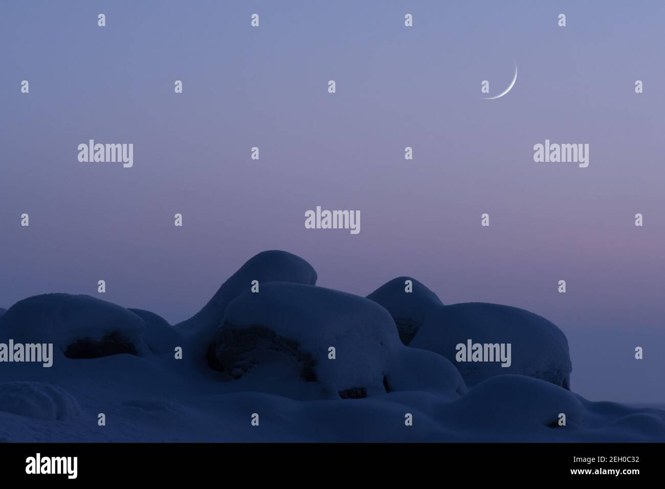 Winter landscape at twilight. Crescent new moon in the sky behind snow ...