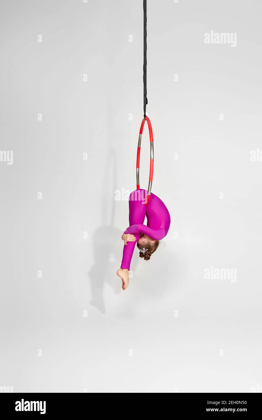 little child girl gymnast in pink sportwear doing acrobatic tricks on ...