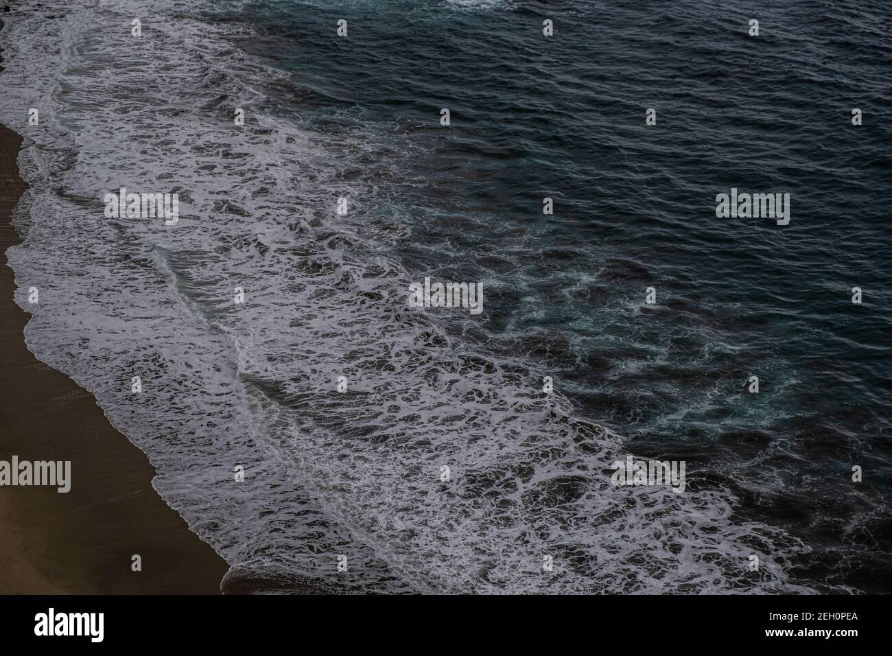 Beautiful view of the wavy ocean hitting the sandy beach in Northern ...