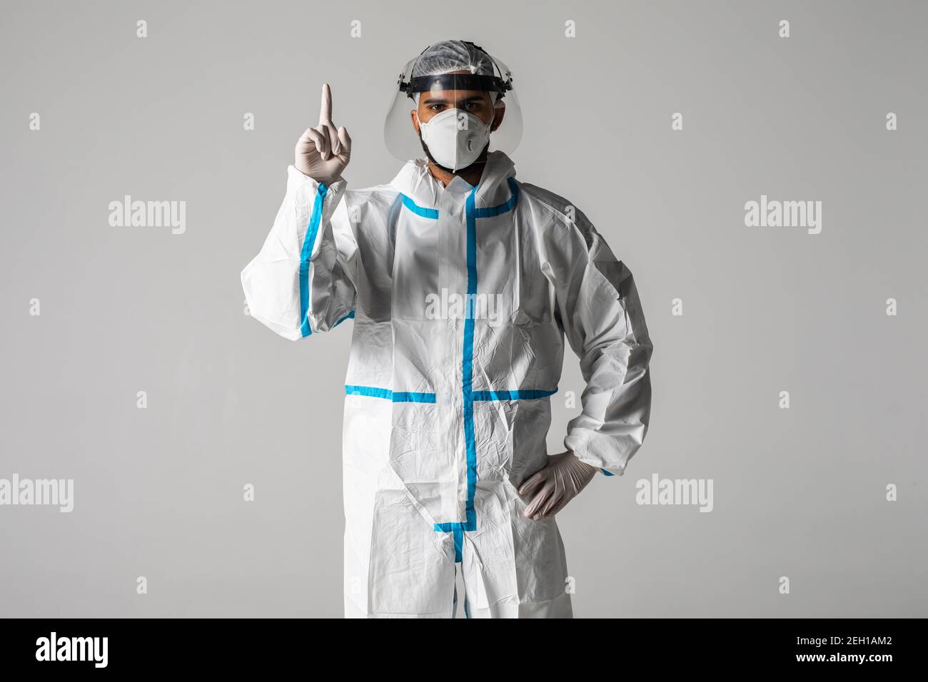 Healthcare worker in protective suit and medical mask pointing finger ...