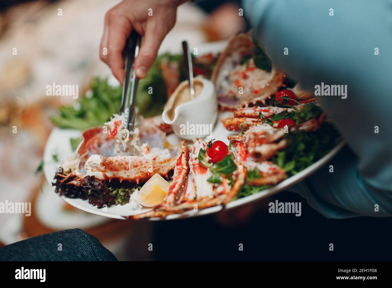 a waiter in a restaurant holds seafood dishes and serves a table ...