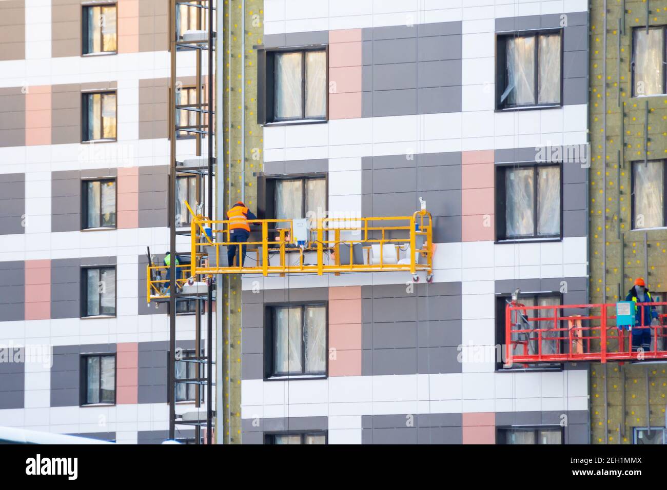 Finishing the facade of residential buildings by workers on the ...