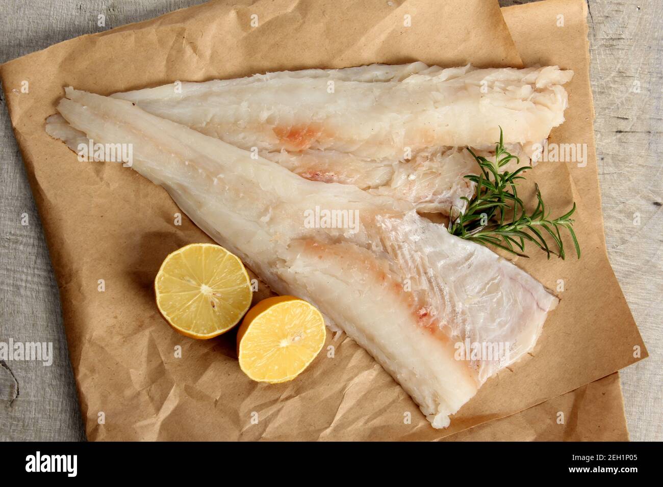 Two Piece of sea fish filet on a paper, decorated with lemon and ...