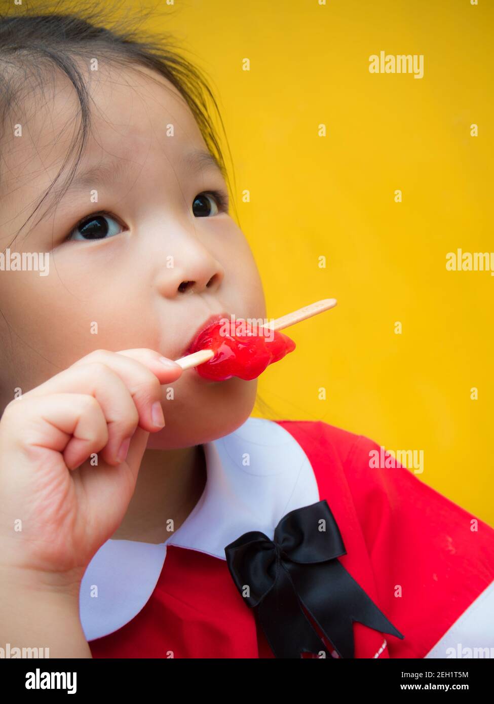 Little girls in red student dressed Eating a red popsicle Stock Photo ...