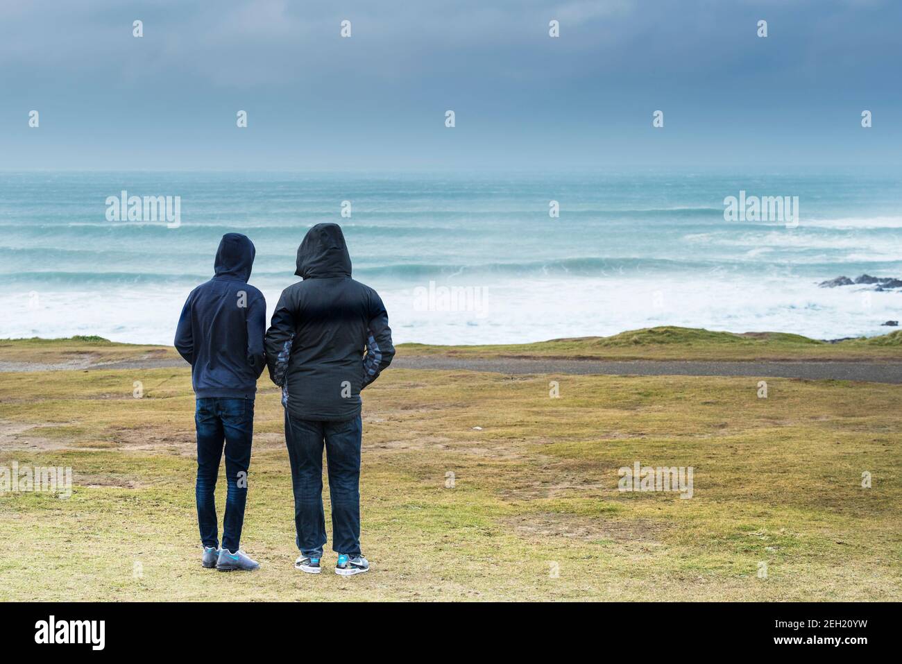 People standing on a coast path looking out to sea and watching waves ...