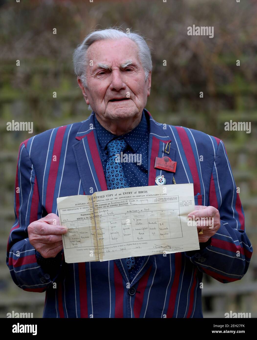 103-year-old Tom Jones holds his birth certificate before walking laps ...
