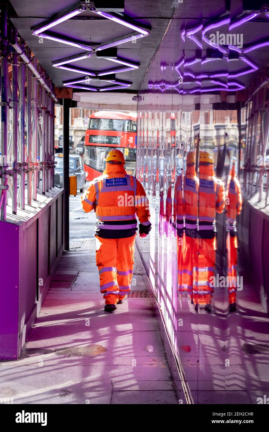 A rear view of an industry Traffic Marshall who walks through a covered ...