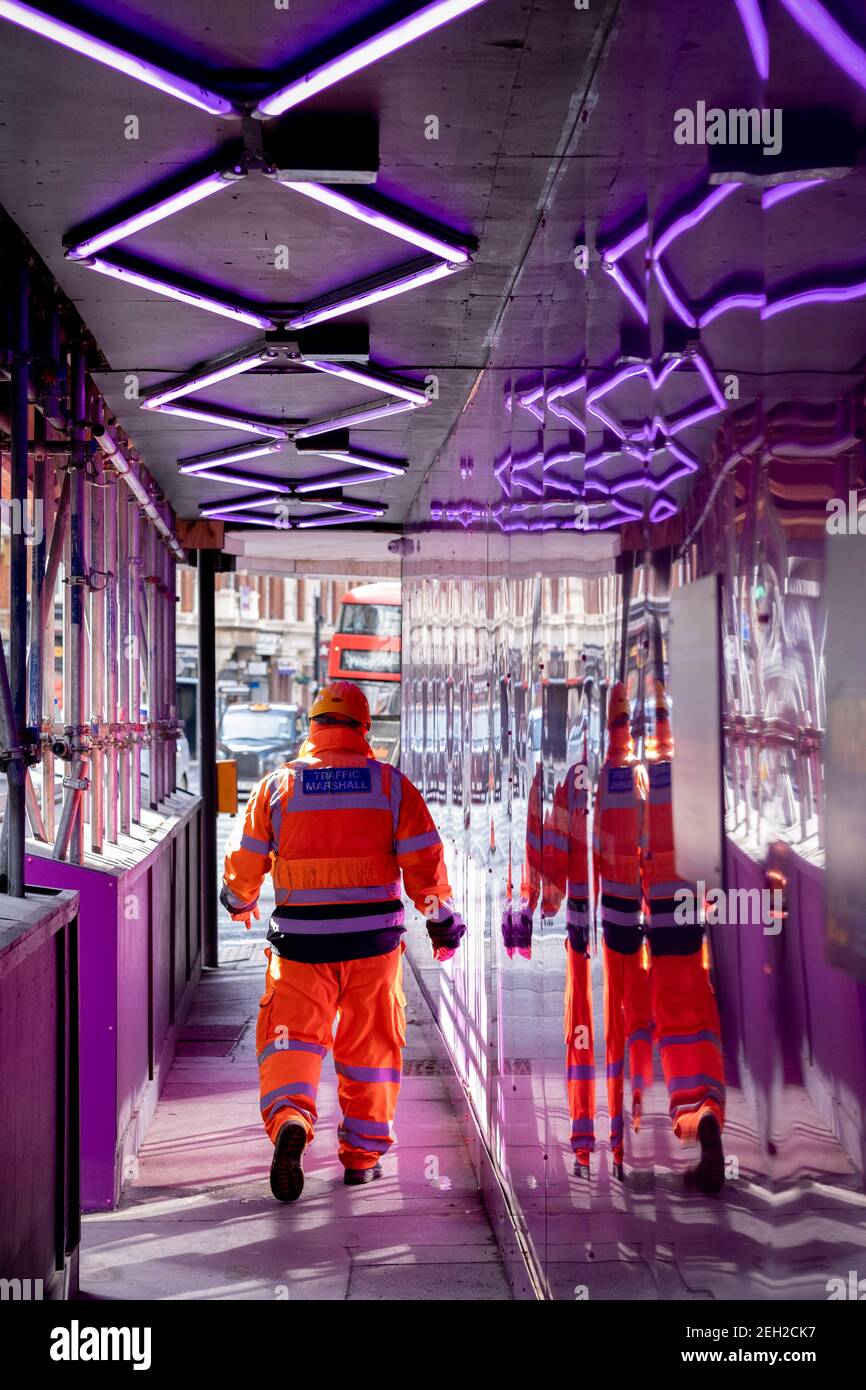 A rear view of an industry Traffic Marshall who walks through a covered ...
