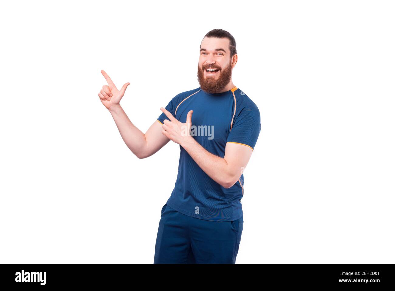 Smiling young fitness man pointing away over white background Stock ...