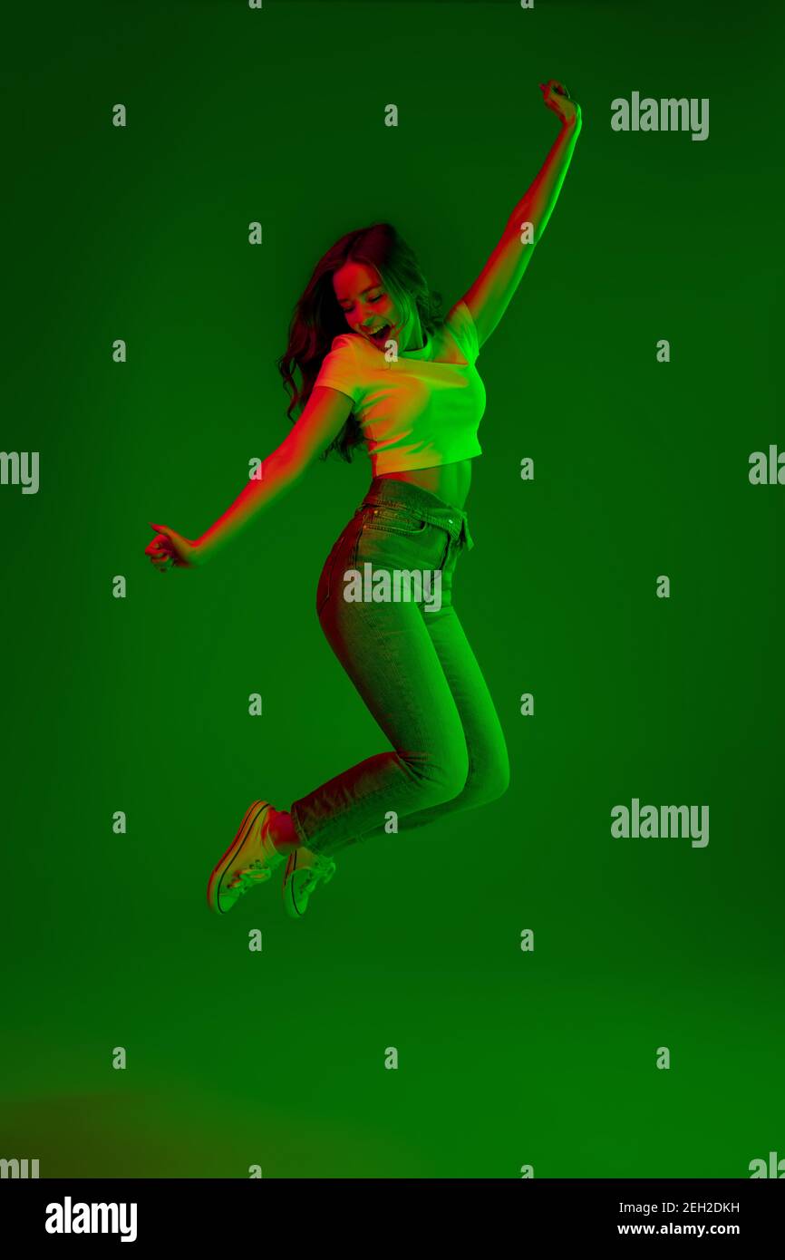 Jumps high. Caucasian woman's portrait on green studio background in ...