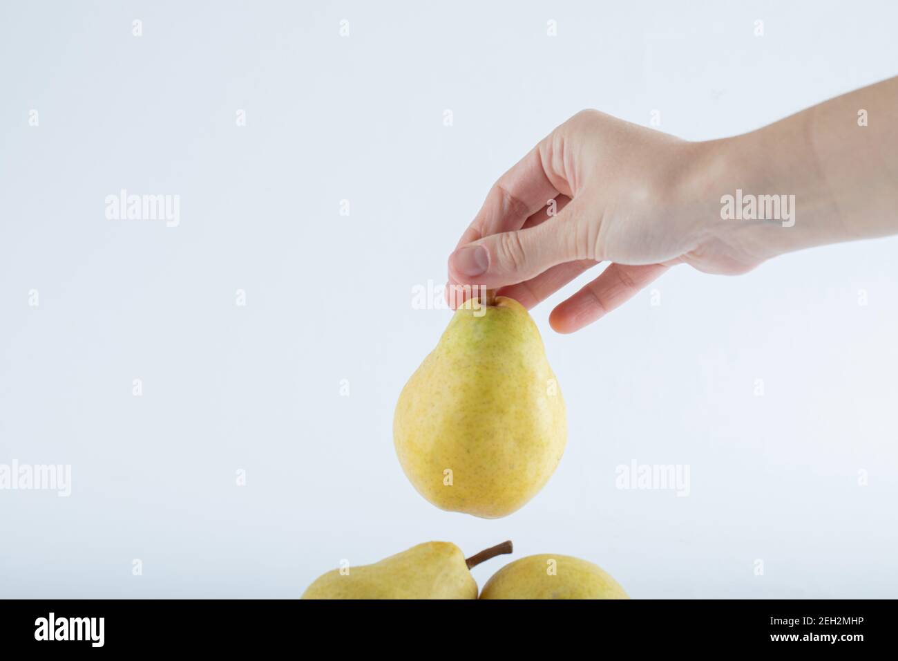 Female hands holding pear on white background Stock Photo - Alamy