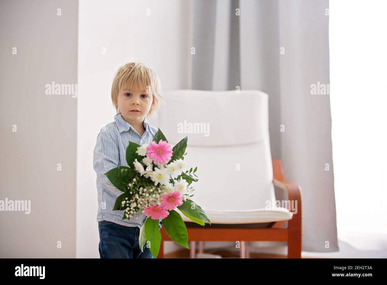 Beautiful blond boy, giving mother flowers and box with little gift for ...