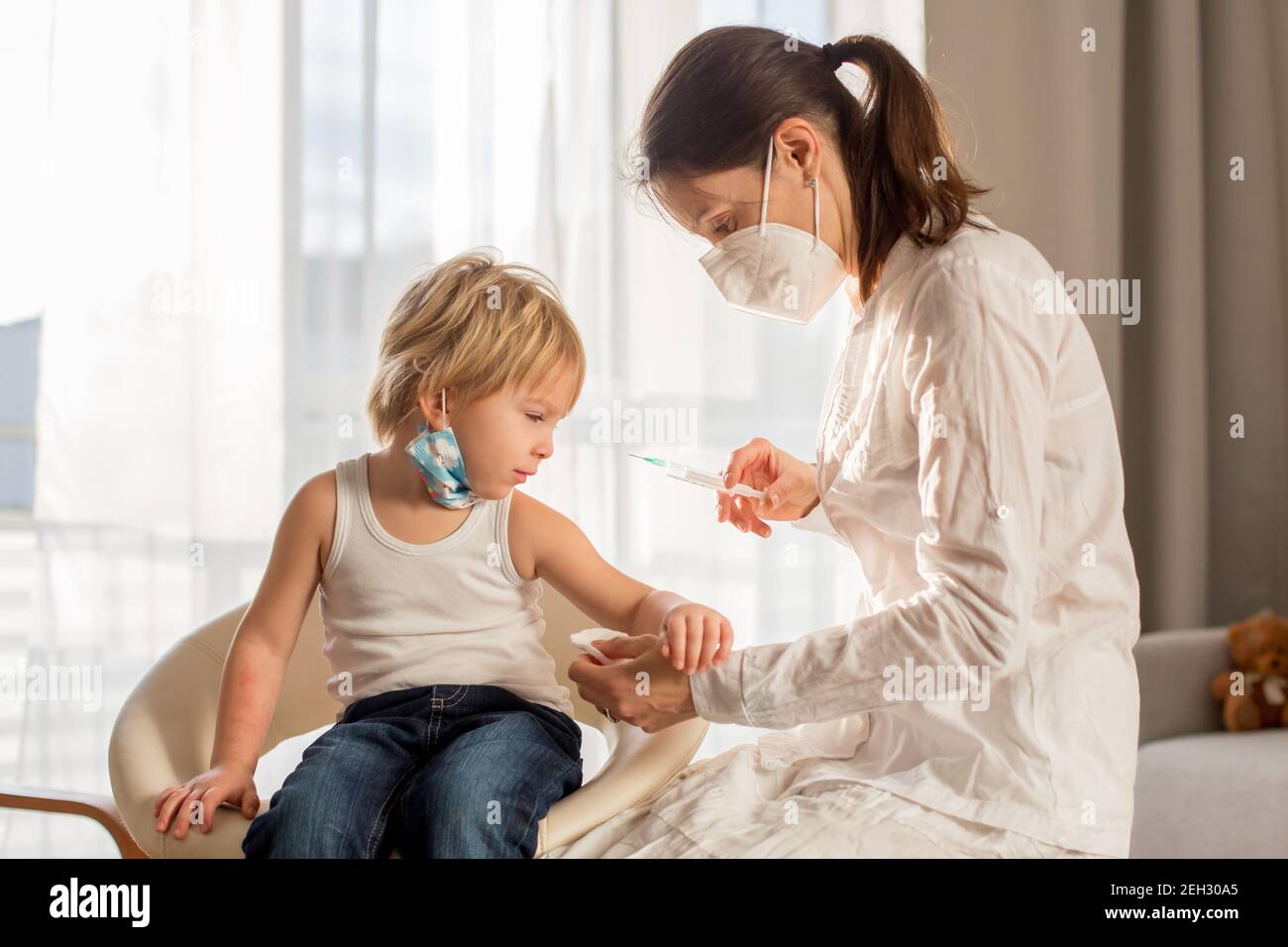 Little toddler child, blond boy, getting injection in consulting room ...