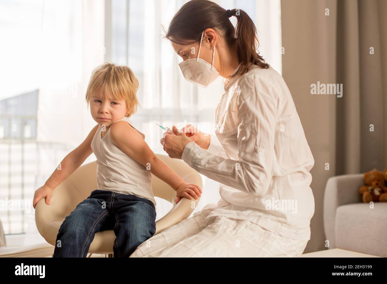 Little toddler child, blond boy, getting injection in consulting room ...