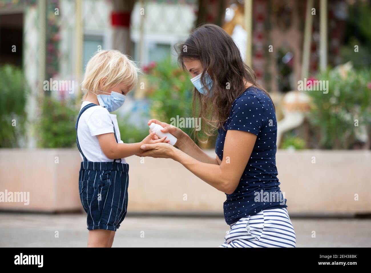 Mother and child, boy and mom, wearing masks and using disinfection ...
