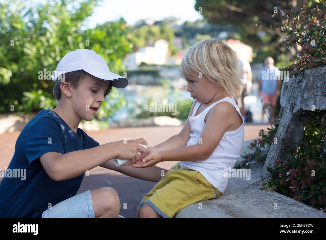 Children, boy brothers, wearing masks and using disinfection outdoors ...