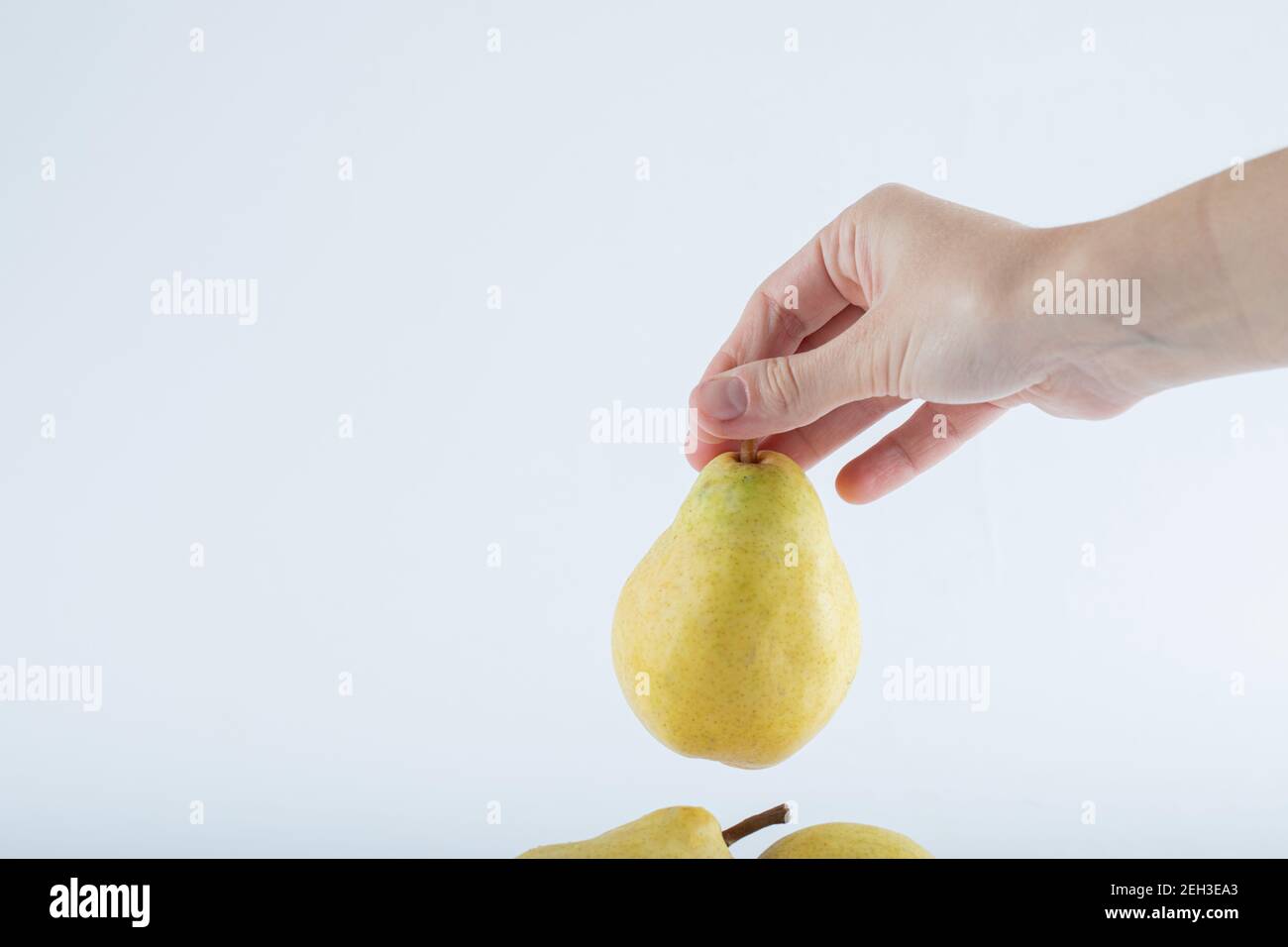 Female hands holding pear on white background Stock Photo - Alamy