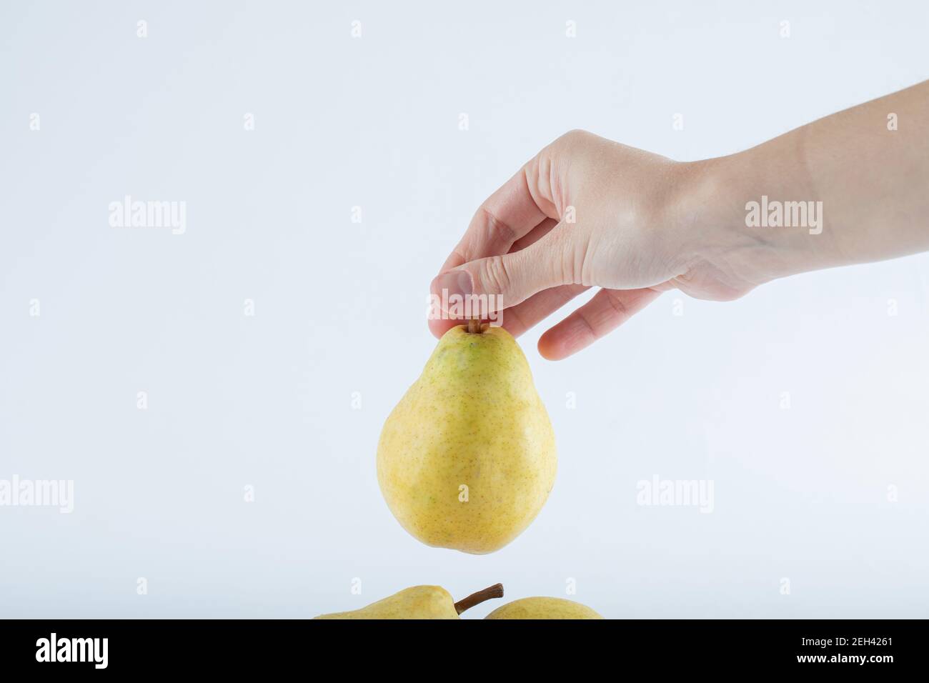 Female hand holding pear on white background Stock Photo - Alamy