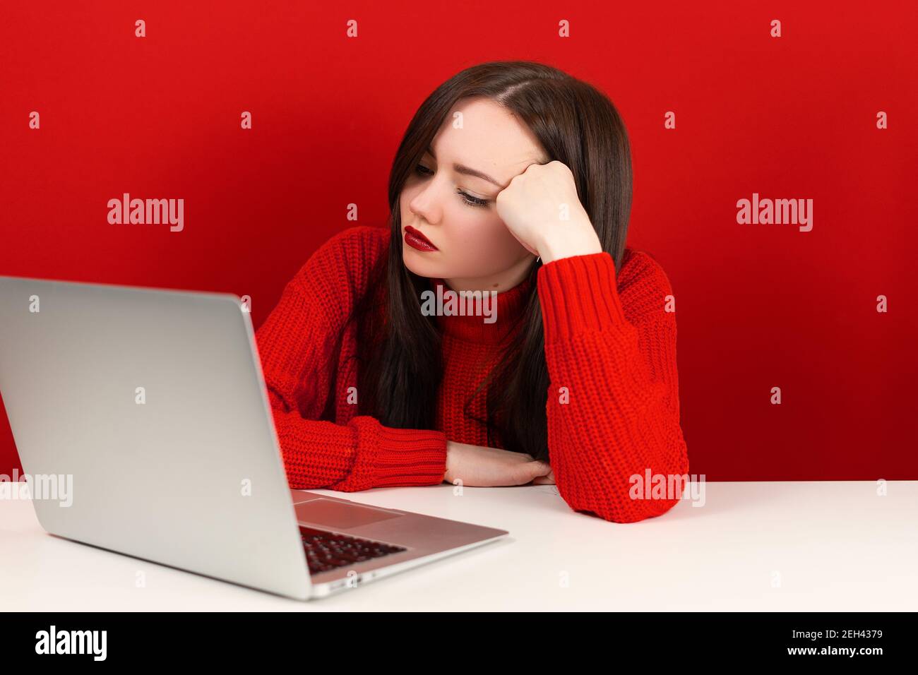 beautiful girl is sad at the computer on a red background Stock Photo ...
