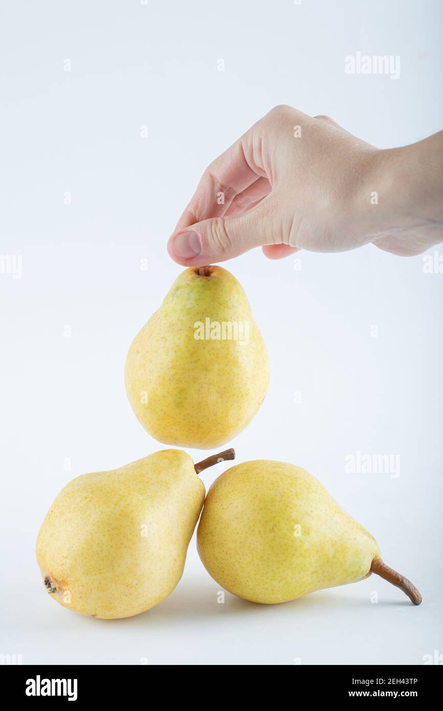 Female hand holding pear on white background Stock Photo - Alamy