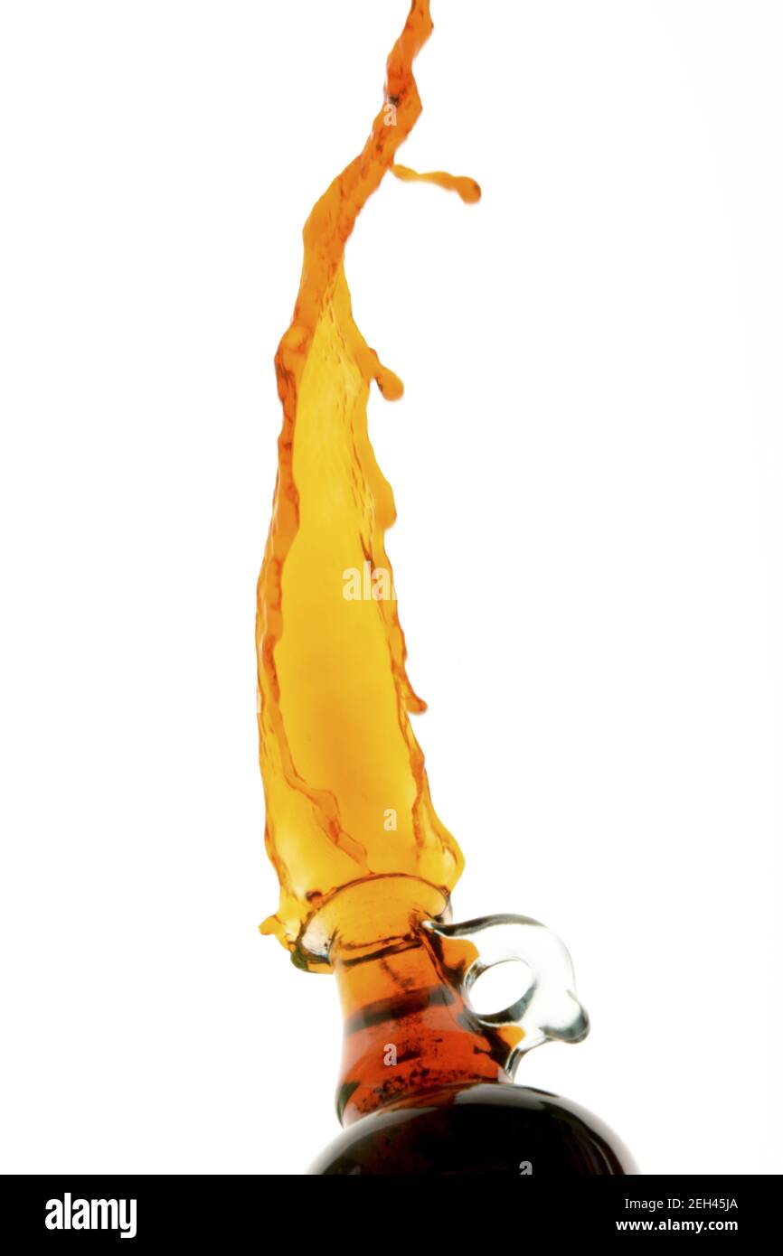 Vertical shot of splashes of dripping liquid from a glass bottle ...