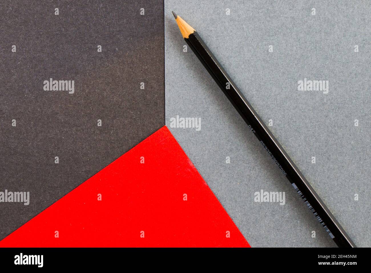 Black pencil on the red and gray paper background Stock Photo - Alamy