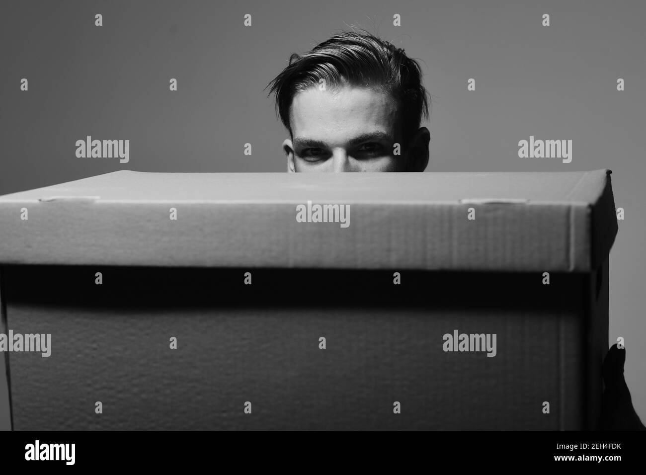 Loader holds box in front of face, close up. Delivery and moving ...