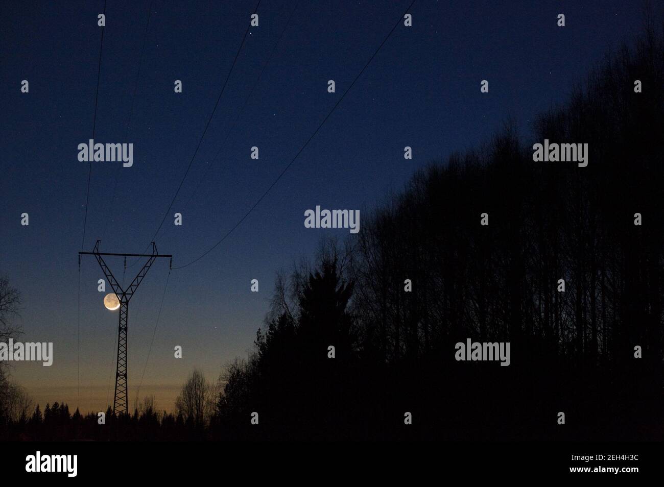 Power line in landscape. Crescent Moon in twilight sky Stock Photo - Alamy
