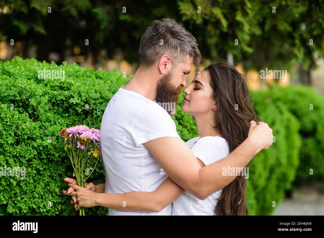 He likes her gorgeous hair. Girl holds flowers while man caress her ...